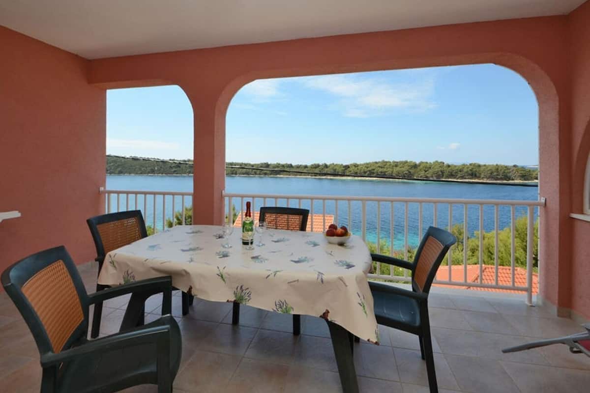 Uma sala de jantar com mesa posta para quatro, com vista para um corpo d'água.