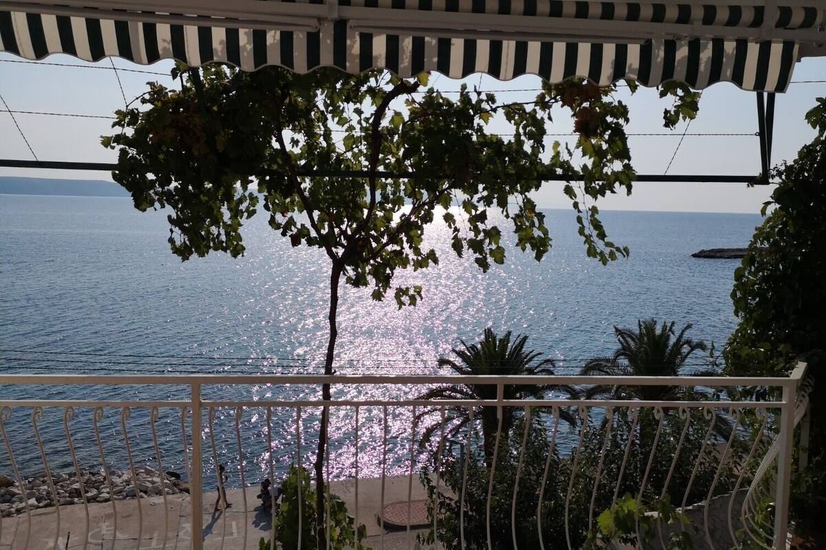 Varanda com vista para o mar, uma árvore e um corrimão.
