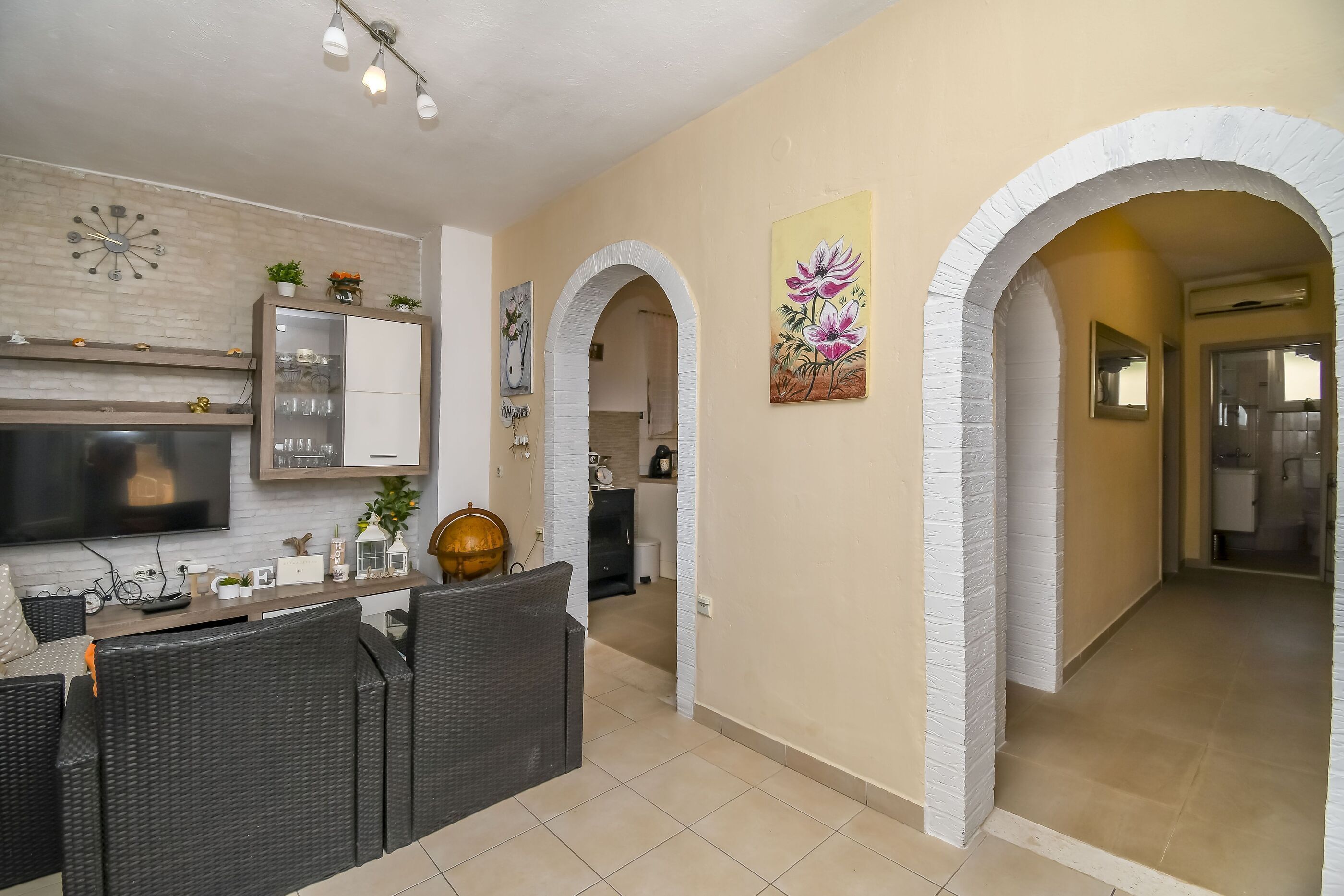 Uma sala de estar moderna com área de jantar, cozinha ao fundo e corredor que dá acesso a outros cômodos.
