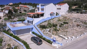 Um edifício costeiro com fachada azul, área externa coberta e um espaço de estacionamento.