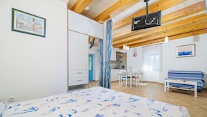 Quarto com cama, mesa de jantar e cozinha.