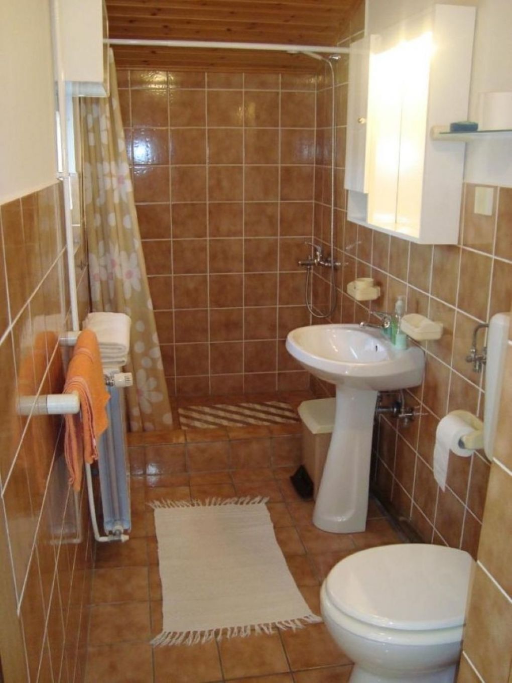 Casa de banho com chuveiro, lavatório e sanita.