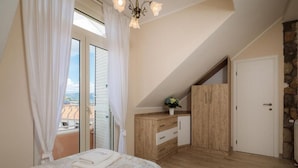 Quarto com duas camas, cômoda de madeira, parede de pedra e varanda com vista.