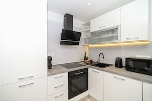 Apartamento (A1) | Cozinha privada | Um frigorífico, um micro-ondas, um forno, uma placa de cozinha 