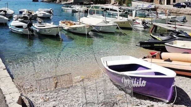 Uma marina com barcos atracados, uma igreja e edifícios numa encosta.