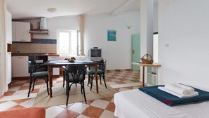 Quarto compacto com mesa de jantar, cadeiras, televisão e cama com toalhas.
