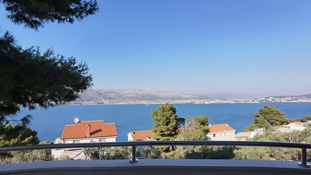 Uma varanda com vista para uma cidade costeira e o mar.