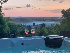 Uma banheira de hidromassagem com vista para a paisagem durante o pôr do sol.