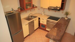 Uma cozinha compacta com geladeira, pia, lava-louças, fogão e armários.