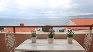 Uma varanda com mesa e cadeiras, com vista para o mar.