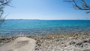 Uma costa rochosa com águas azul-claras e montanhas ao longe.