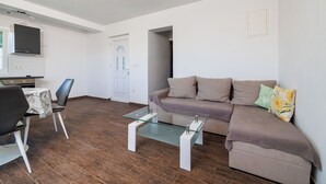 Uma sala de estar moderna com uma mesa de centro de vidro, um sofá e um espaço de jantar com mesa e cadeiras.