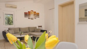 Uma sala de estar moderna com um sofá, uma mesa de centro e uma mesa de jantar com tulipas amarelas.