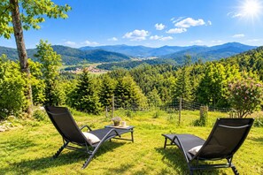 Duas cadeiras de descanso voltadas para uma paisagem montanhosa com céu limpo.