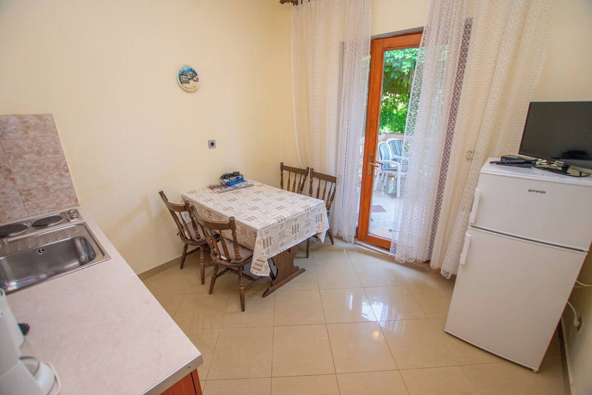 Uma cozinha compacta com mesa, cadeiras, geladeira e pia.