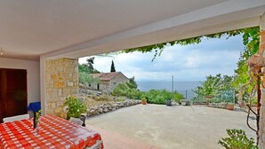 Um pátio com toalha de mesa xadrez vermelha e branca, paredes de pedra e plantas em vasos.