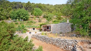Uma casa de pedra com um muro de pedra e um pequeno pátio.