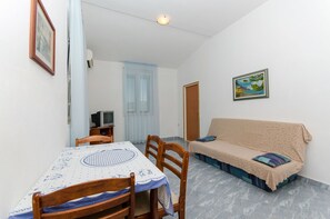 Um quarto com uma mesa de jantar, cadeiras, um sofá, uma televisão e um quadro na parede.