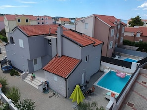 Um edifício residencial com telhado de telhas vermelhas, piscina e área de estar ao ar livre.