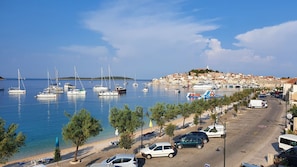 Uma marina costeira com barcos, uma praia e uma cidade ao fundo.
