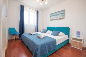 Quarto com cama, cadeira, mesa de cabeceira e um quadro na parede.