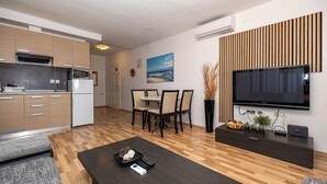 Um espaço de estar moderno com cozinha, área de jantar e TV fixada na parede.