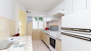 Uma cozinha compacta com geladeira, micro-ondas, forno e uma mesa de jantar com cadeiras.