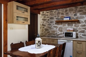 Cozinha com armários de madeira, parede de pedra, micro-ondas e lava-louças.