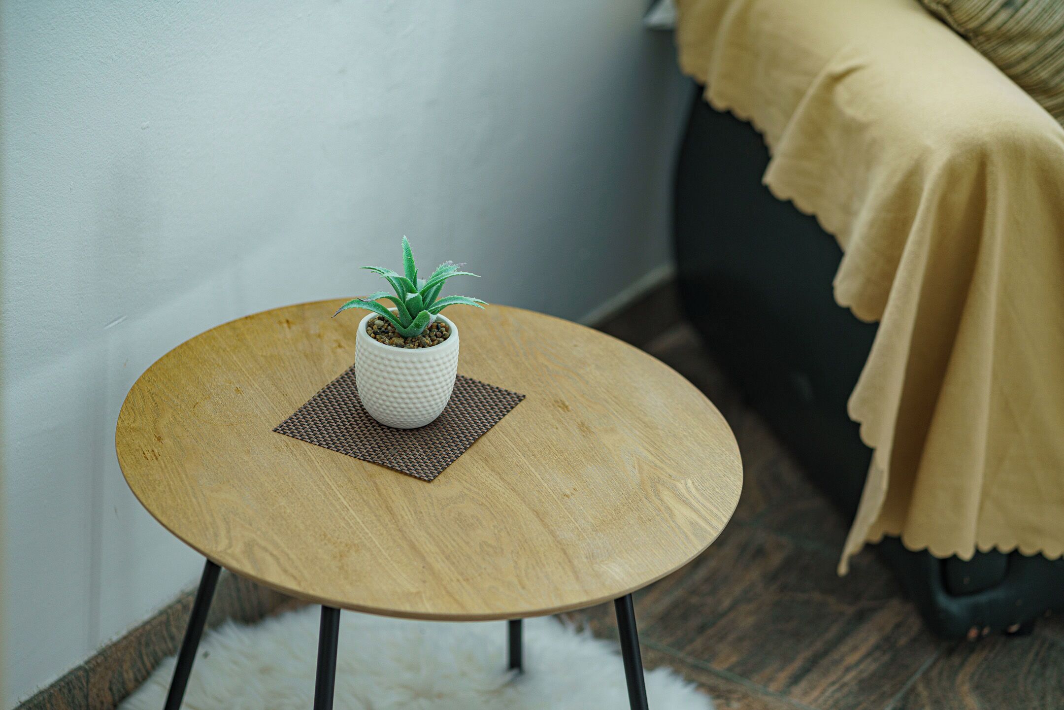 Uma pequena mesa de madeira com uma planta em vaso sobre um apoio de mesa texturizado.