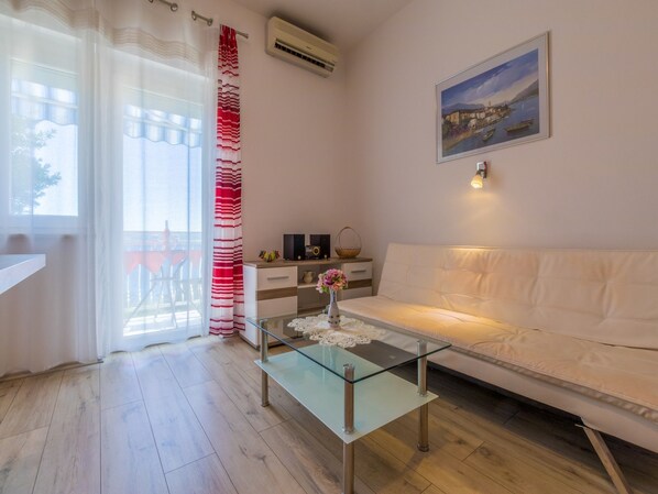 Uma sala de estar moderna com mesa de centro de vidro, sofá branco e um quadro na parede.