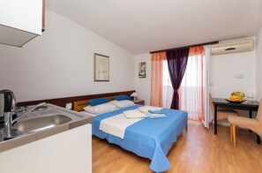 Quarto de hotel com cama, escrivaninha, cadeira, pia e ar condicionado.