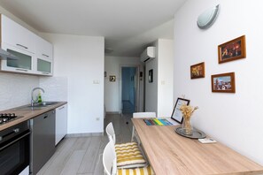 Uma cozinha moderna com armários brancos, bancada de madeira e uma área de refeições com mesa e cadeiras de madeira.