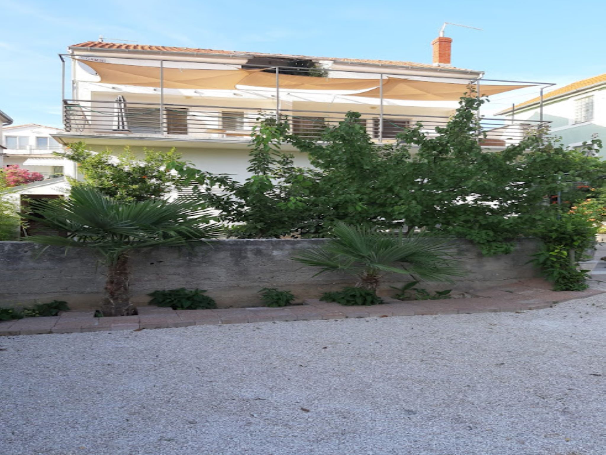 Um edifício com varanda, parede de concreto e vegetação.