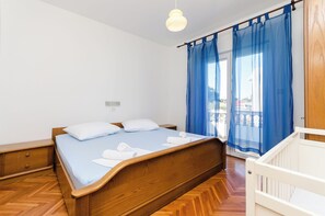Quarto com cama de madeira, almofadas brancas e cortinas azuis.