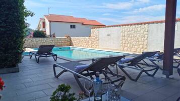Área de piscina com espreguiçadeiras e uma mesa com copos e garrafa.