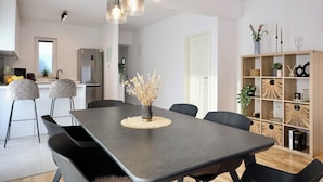 Cozinha moderna com área de jantar, apresentando uma mesa grande, cadeiras e um vaso decorativo.