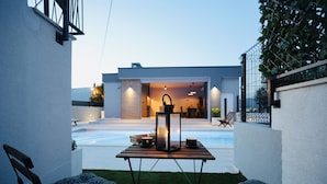 Um pátio moderno ao ar livre com piscina, uma mesa com lanterna e duas cadeiras.