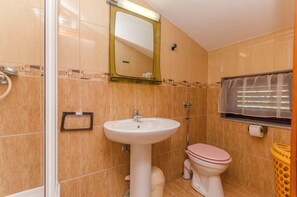 Casa de banho com lavatório, sanita e chuveiro.