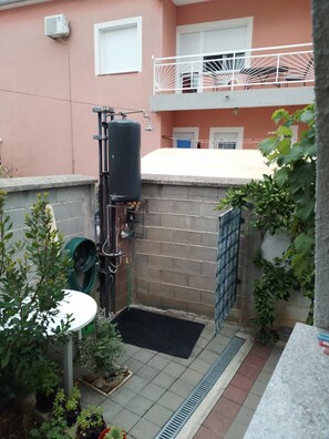 Pequeno espaço ao ar livre com um reservatório de água, mangueira e parede de tijolos.