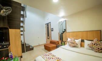 Quarto de hotel com cama, sofá, mesinha, espelho e escada.