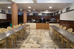 Sala de conferências com uma mesa comprida, cadeiras e um balcão com funcionários.