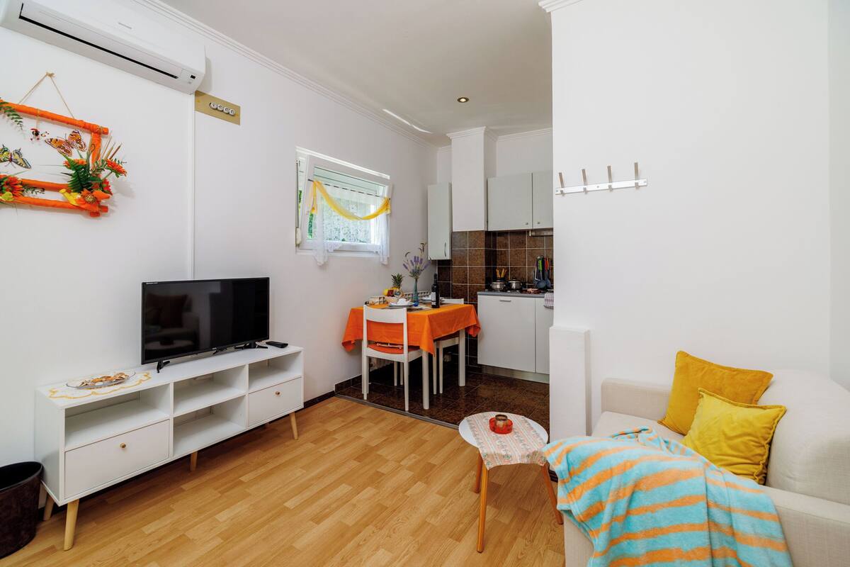 Uma sala de estar moderna com televisão, uma mesa de jantar e uma cozinha.