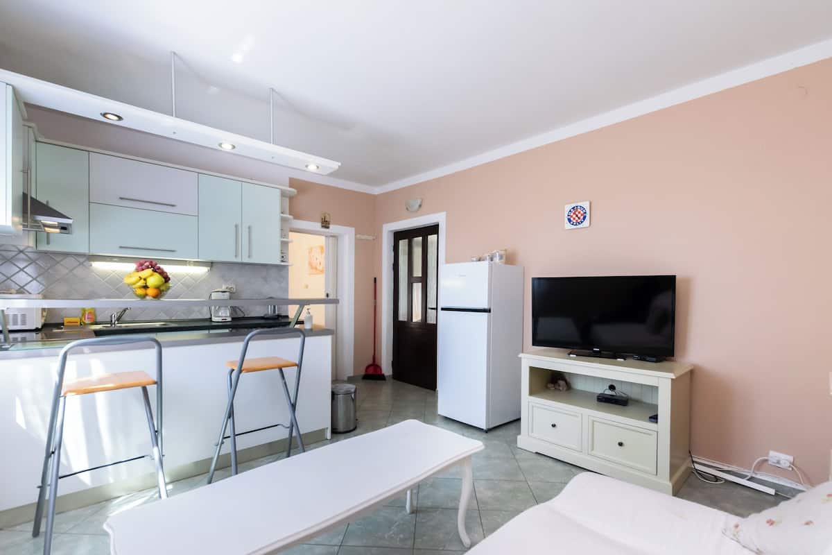 Uma cozinha compacta com área de refeições, televisão e um banco.
