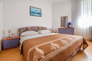 Quarto com cama, mesa de cabeceira, cômoda, espelho e um quadro na parede.