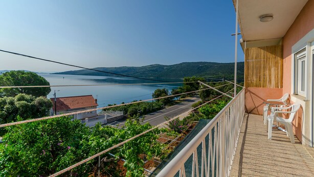 Varanda com vista para um lago e colinas ao longe.