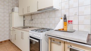 Uma cozinha com armários brancos, fogão, forno e micro-ondas.