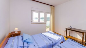 Quarto com cama, mesa de cabeceira, abajur e janela com cortinas.
