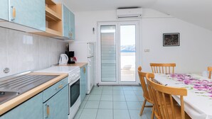 Uma cozinha compacta com área de jantar, com fogão, forno, micro-ondas e uma mesa com cadeiras.
