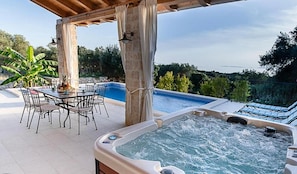 Uma banheira de hidromassagem, piscina ao ar livre e área de refeições com cadeiras e mesa.