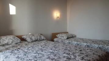 Quarto com duas camas, cada uma com roupa de cama estampada com motivos florais e cabeceiras de madeira.